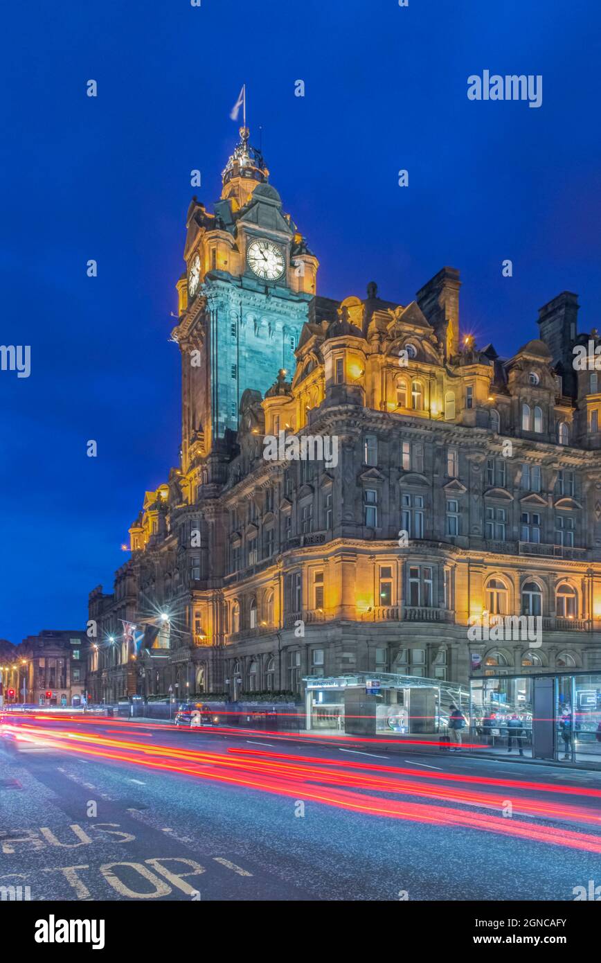 Clock tower of Balmoral Hotel lit up at night with traffic light blur ...