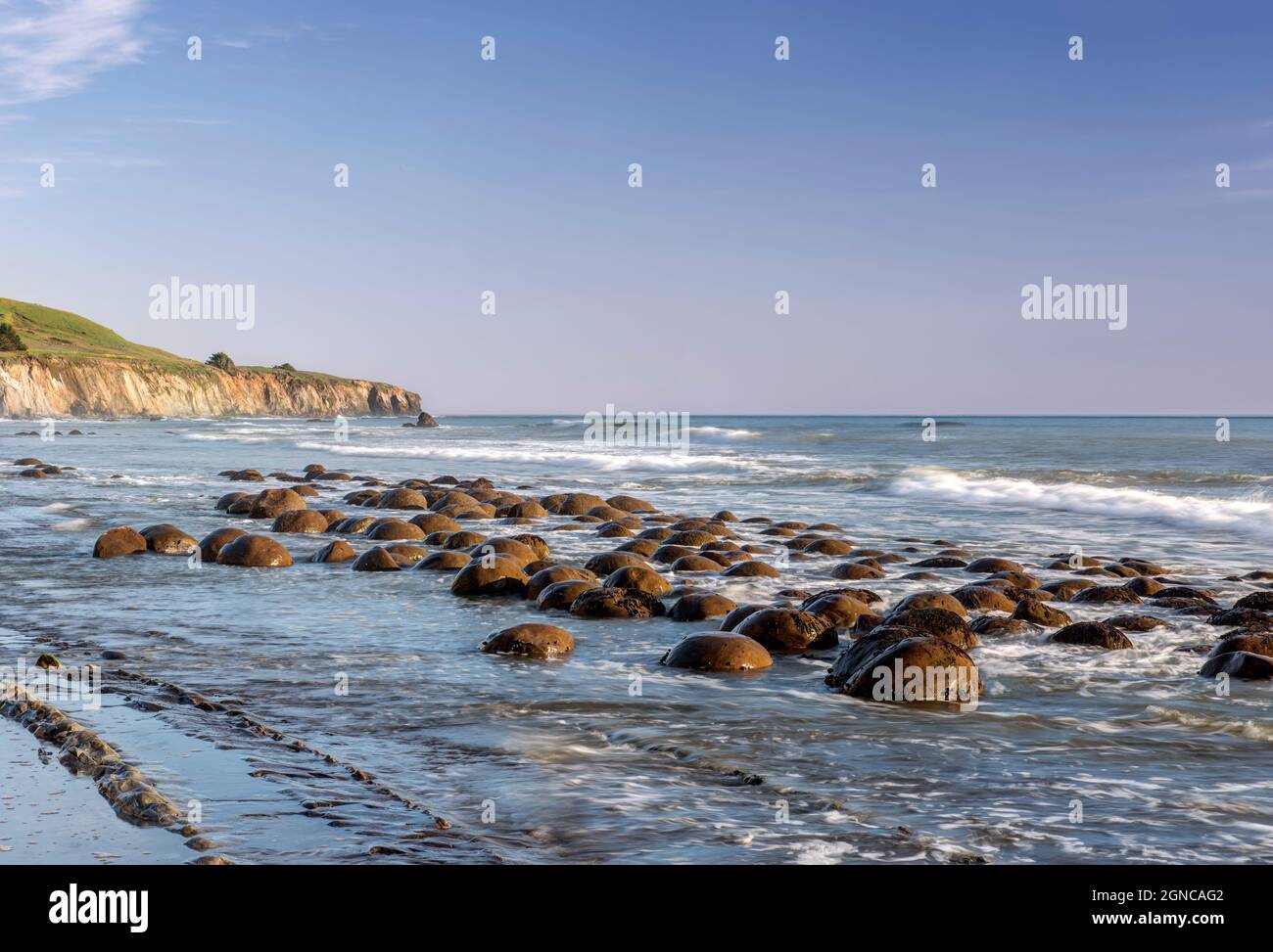 Rocks in shallow waves on Pacific Ocean at dusk Stock Photo - Alamy