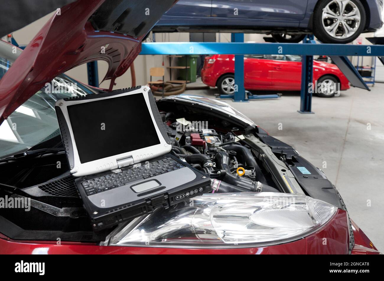 Car in a workshop and a computer running diagnostics on the engine ...