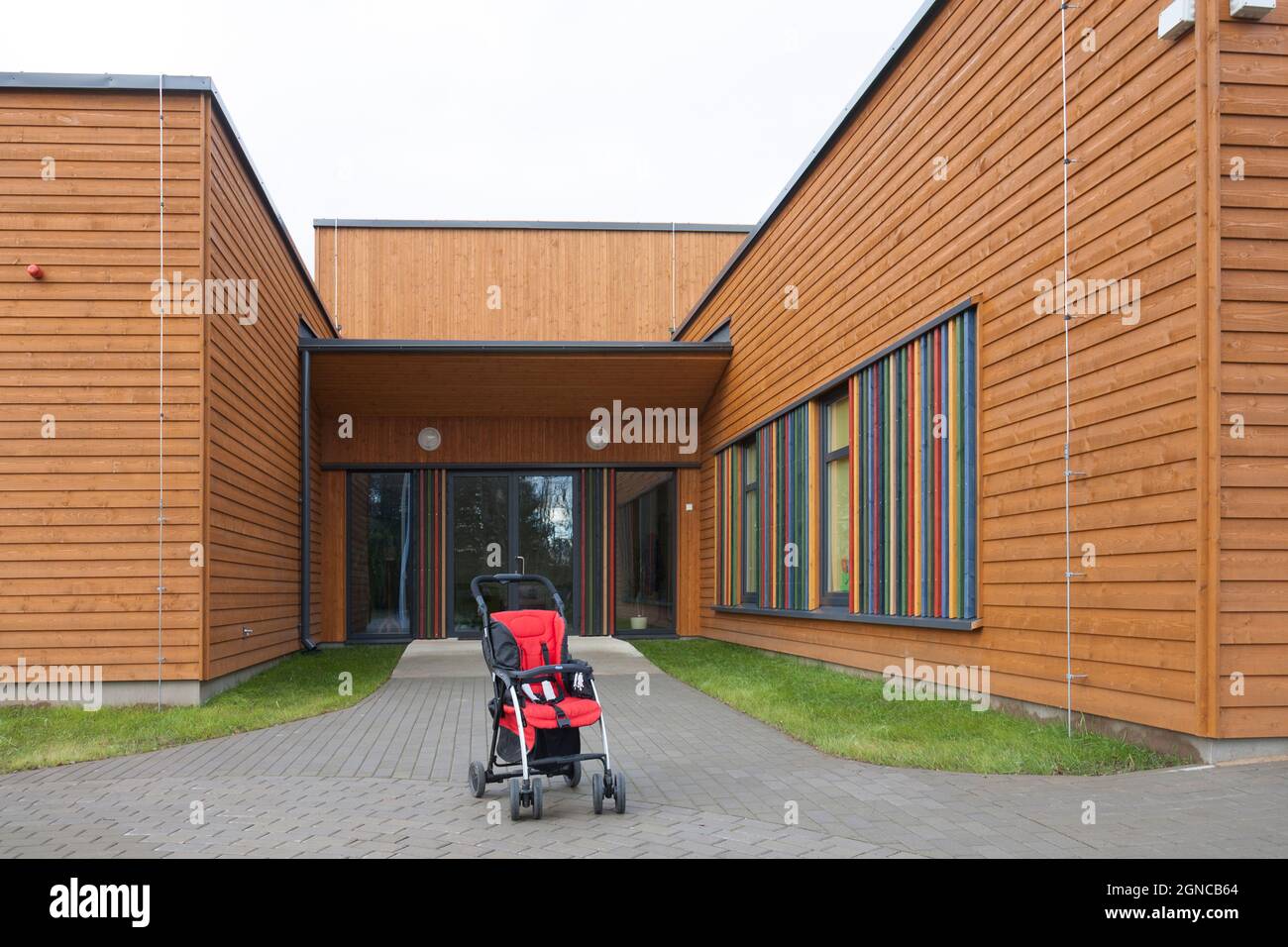 Child's buggy pushchair with a red seat outside a modern day care or ...