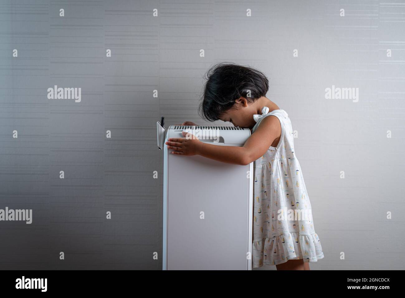 Young child hugging a radiator in front of a gray wall Stock Photo - Alamy