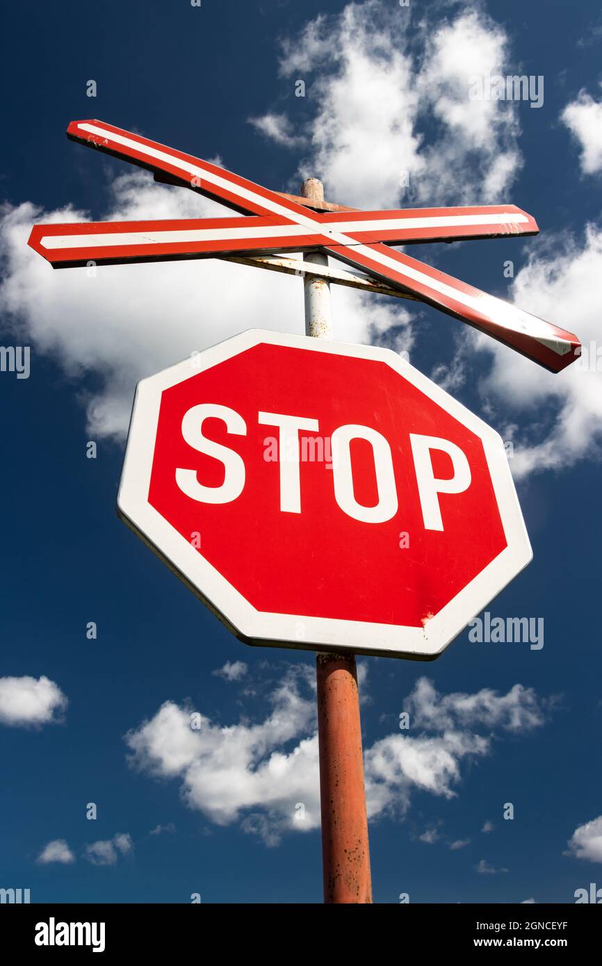 Traffic stop sign at a railway crossing, at background of blue sky ...