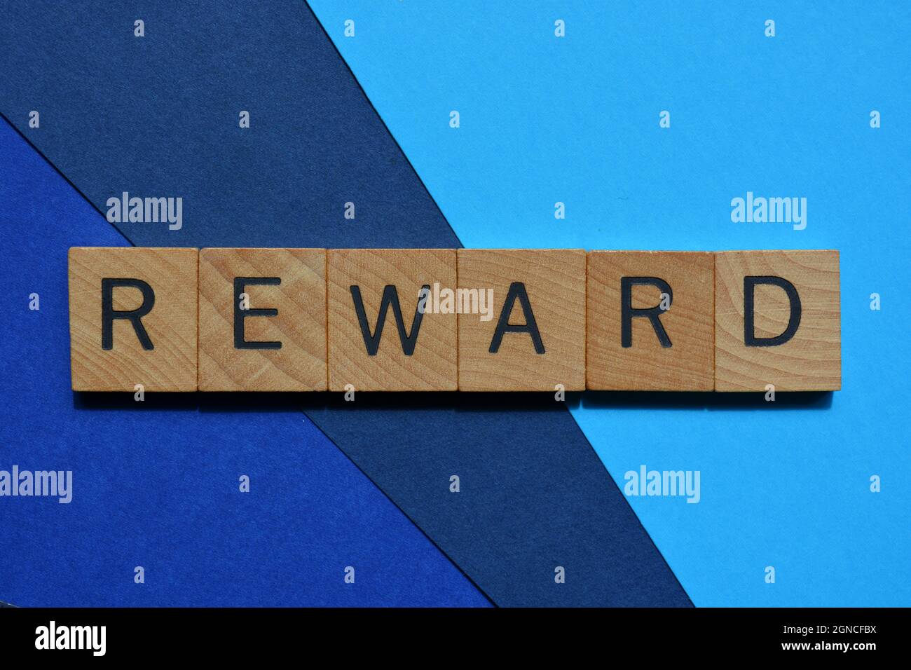 Reward, word in wooden alphabet letters isolated on blue background as ...
