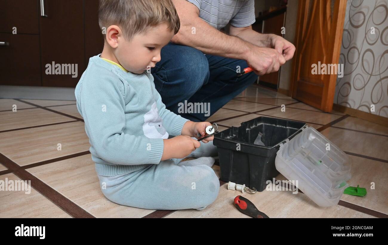 Little boy playing with father's tools on the floor. Clever boy playing ...
