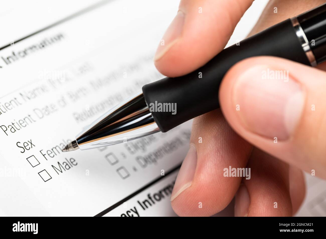 Person holding pen over male female gender option checkboxes in a ...