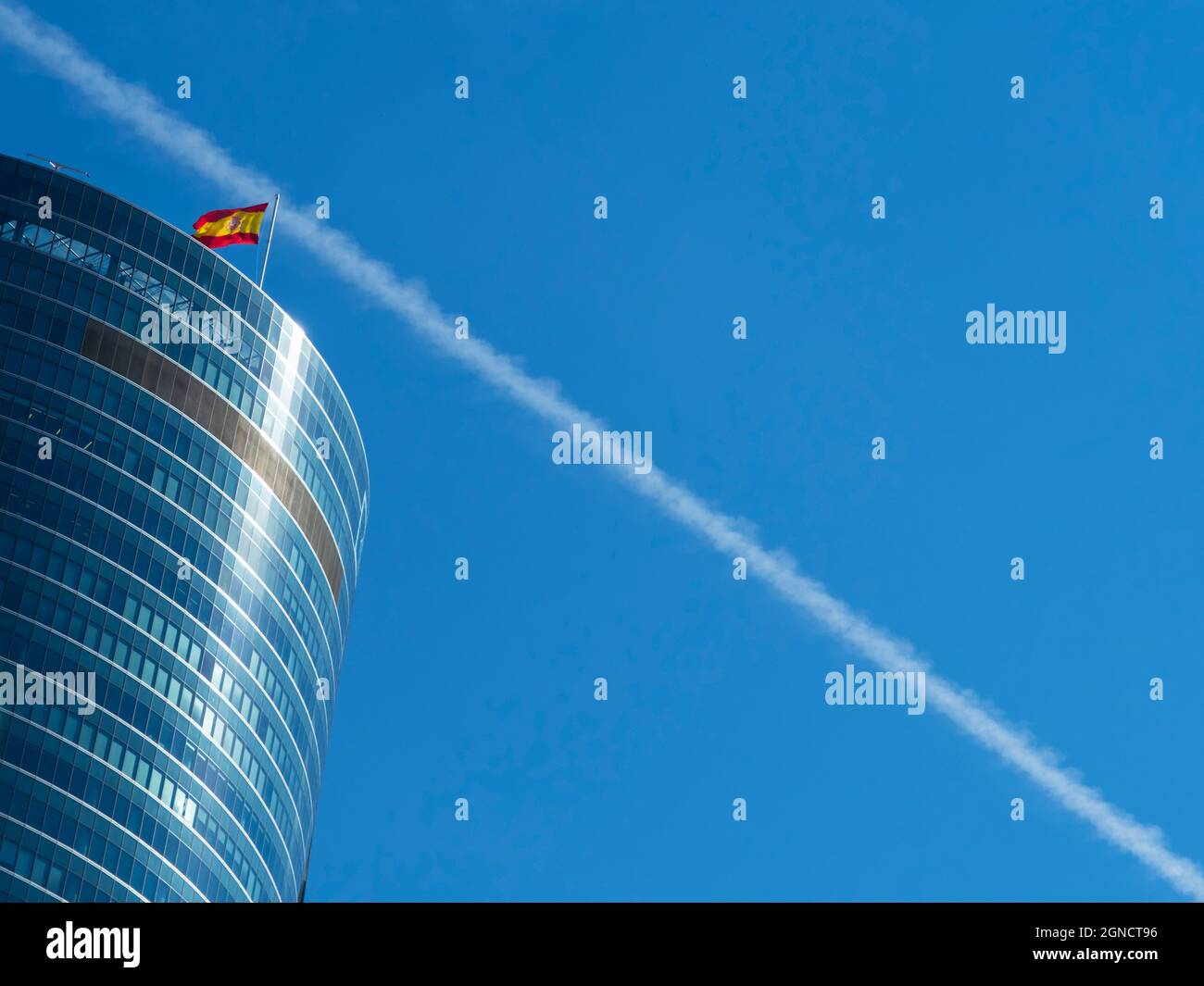 Wake of an airplane over a skyscraper with the flag of Spain Stock ...