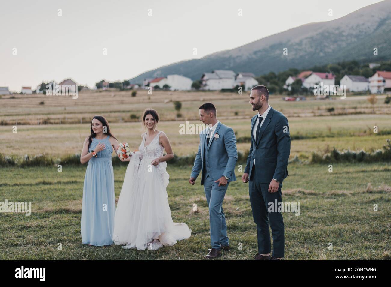 Cheerful married couple with their friends having fun in a hayfield on ...