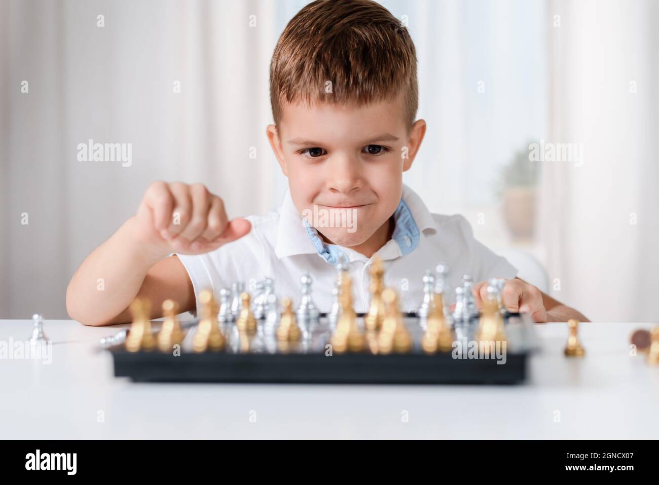 Smart child learns to play chess by himself in his room at home Stock ...