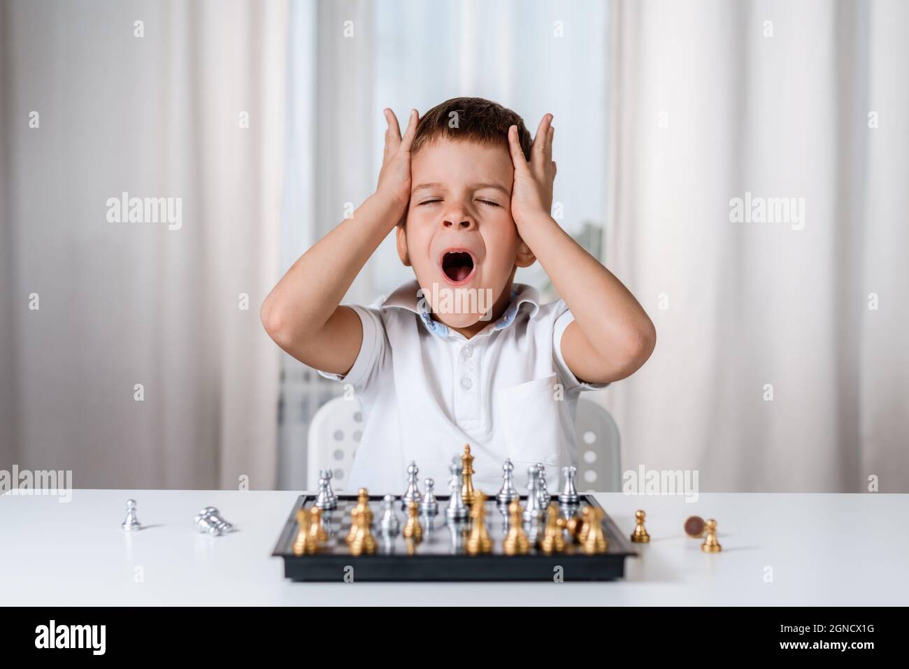 Happy boy enthusiastically playing chess at home Stock Photo - Alamy