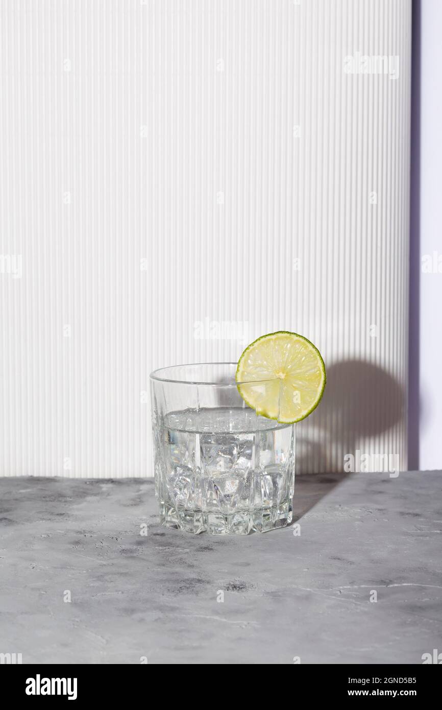 Vodka with ice and lime in glass on white background. Shadows and ...