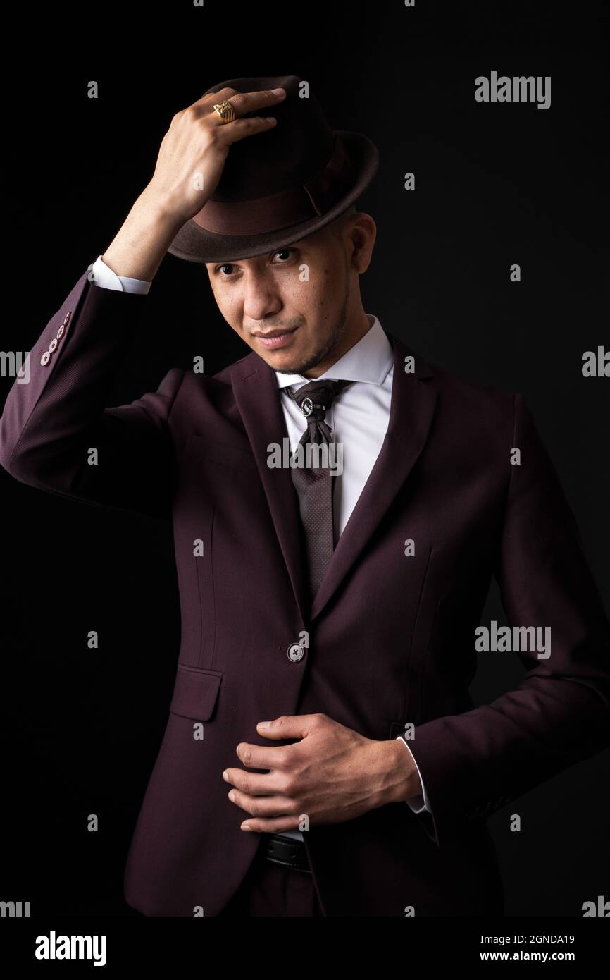 Caucasian man from Spain in suit on black background with hand on hat ...