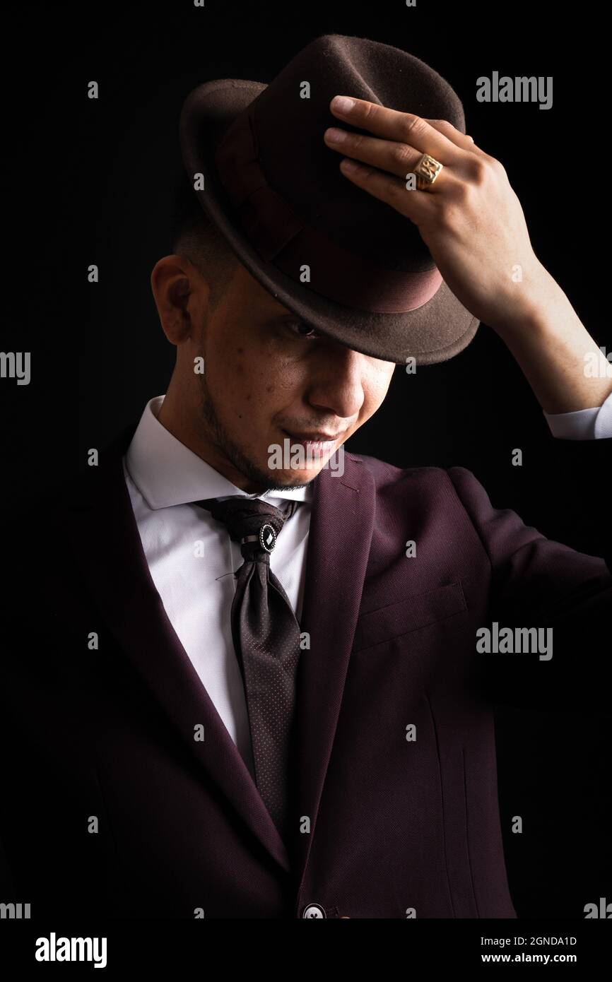Caucasian man from Spain in suit on black background with hand on hat ...