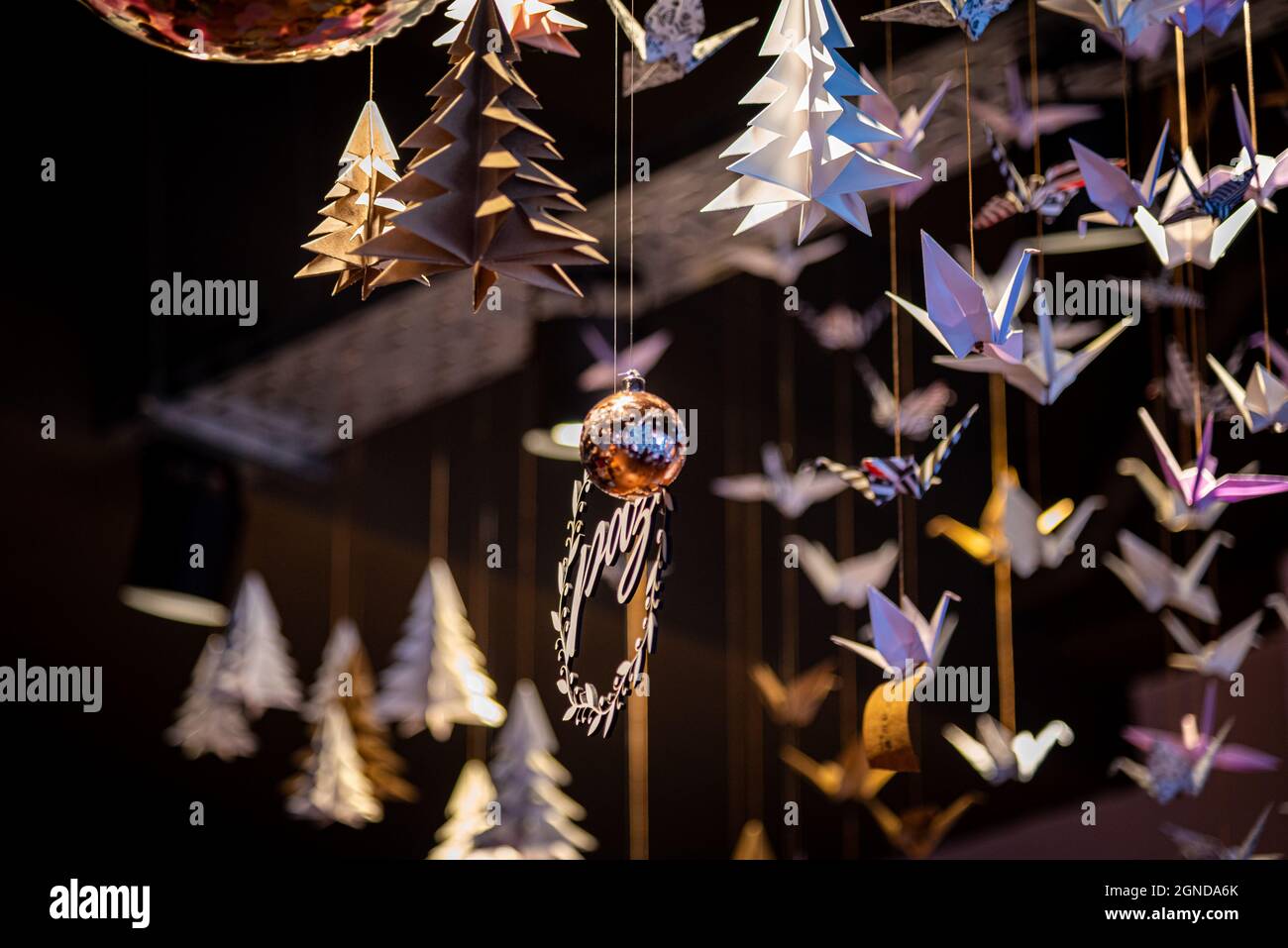 Lots of origami swans hanging from the roof, seen from underneath in a ...