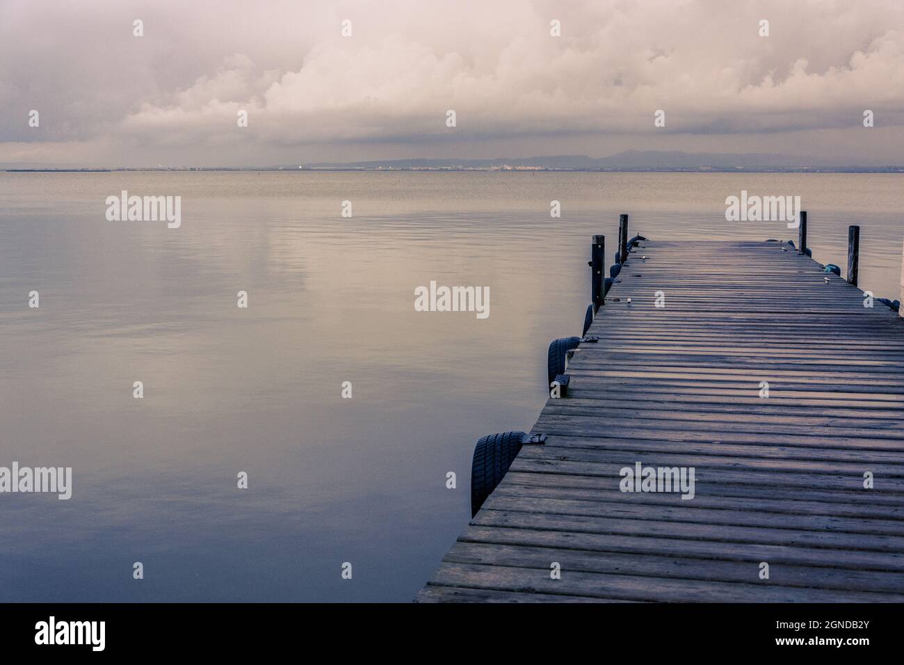 Wooden dock on the water under a cloudy sky on a gloomy day in Valencia ...