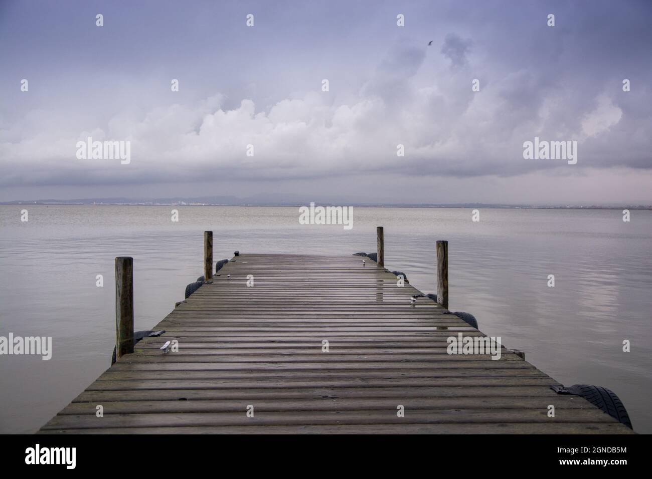 Wooden dock on the water under a cloudy sky on a gloomy day in Valencia ...