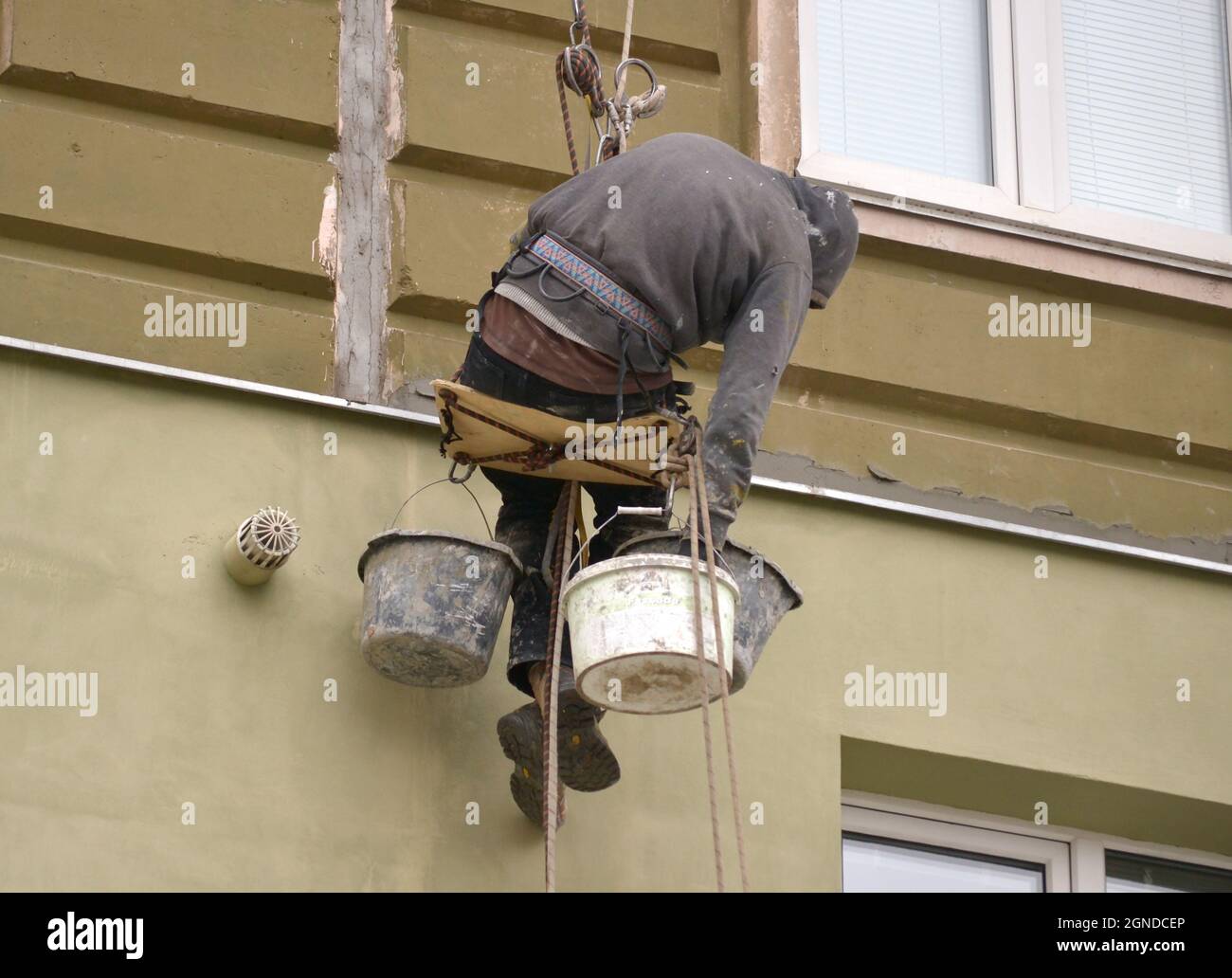 The man works on high-rise works cladding, plastering of the house ...