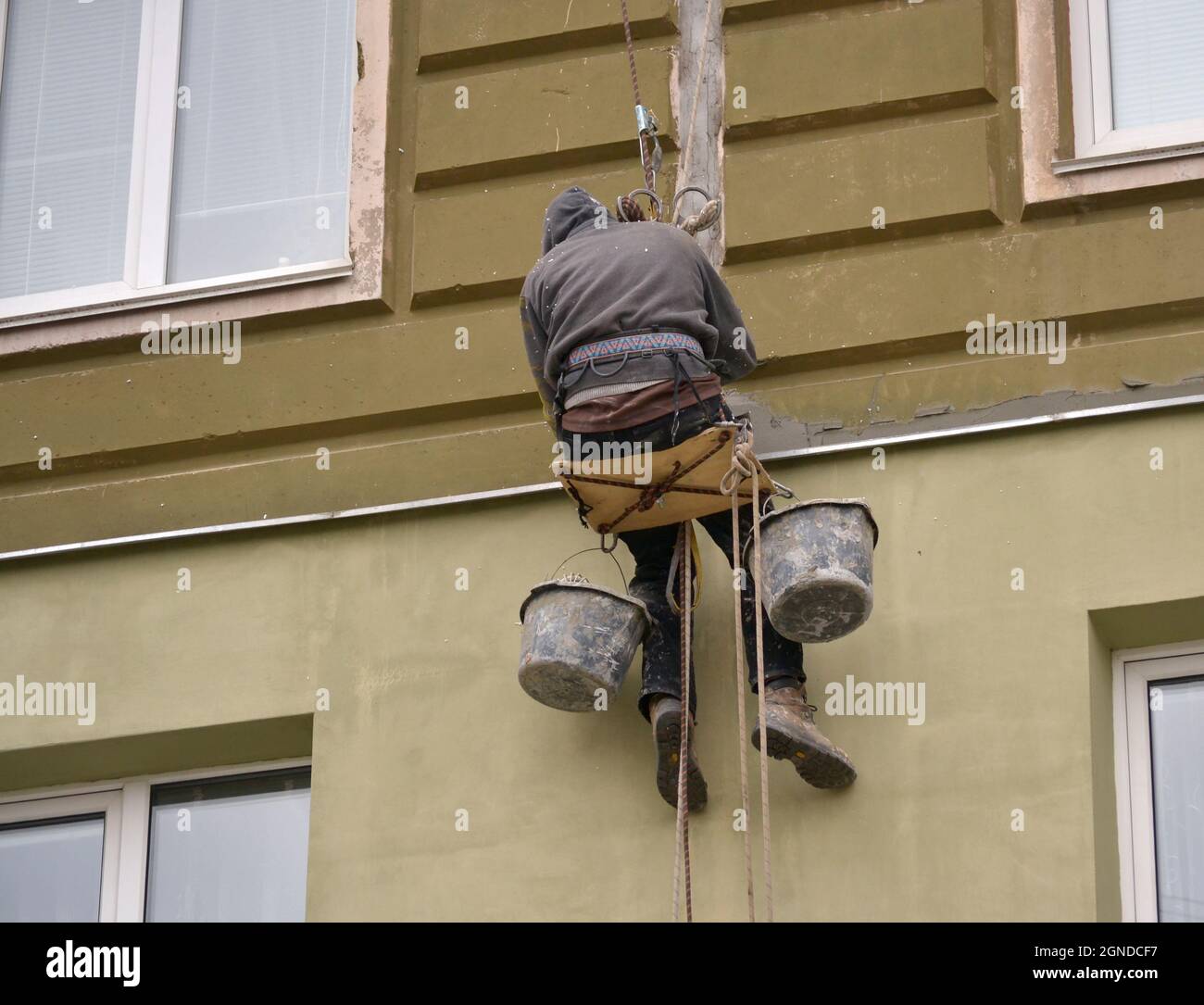 The man works on high-rise works cladding, plastering of the house ...