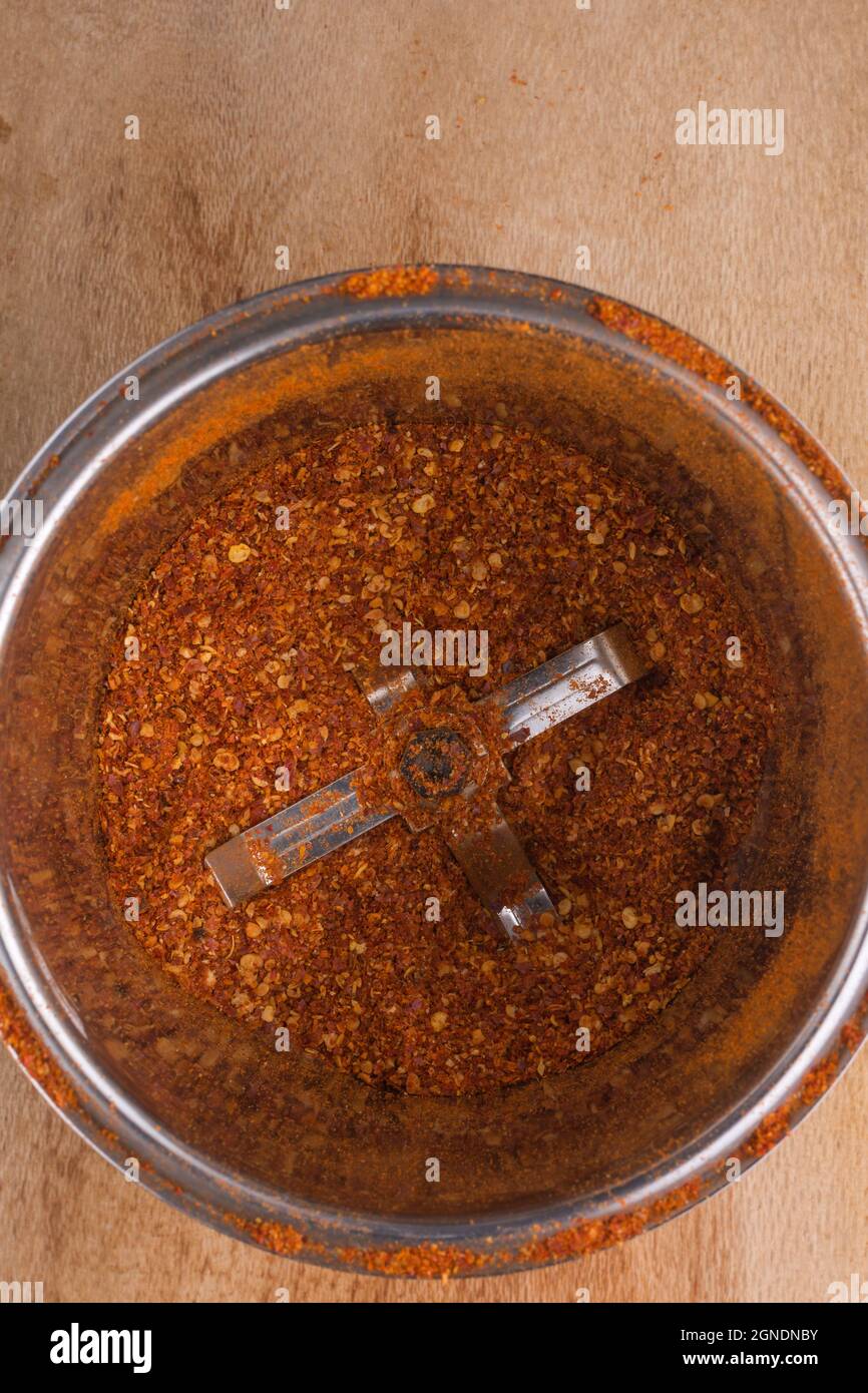 ground dried red chilli, spicy pepper powder on a grinder cup, closeup ...