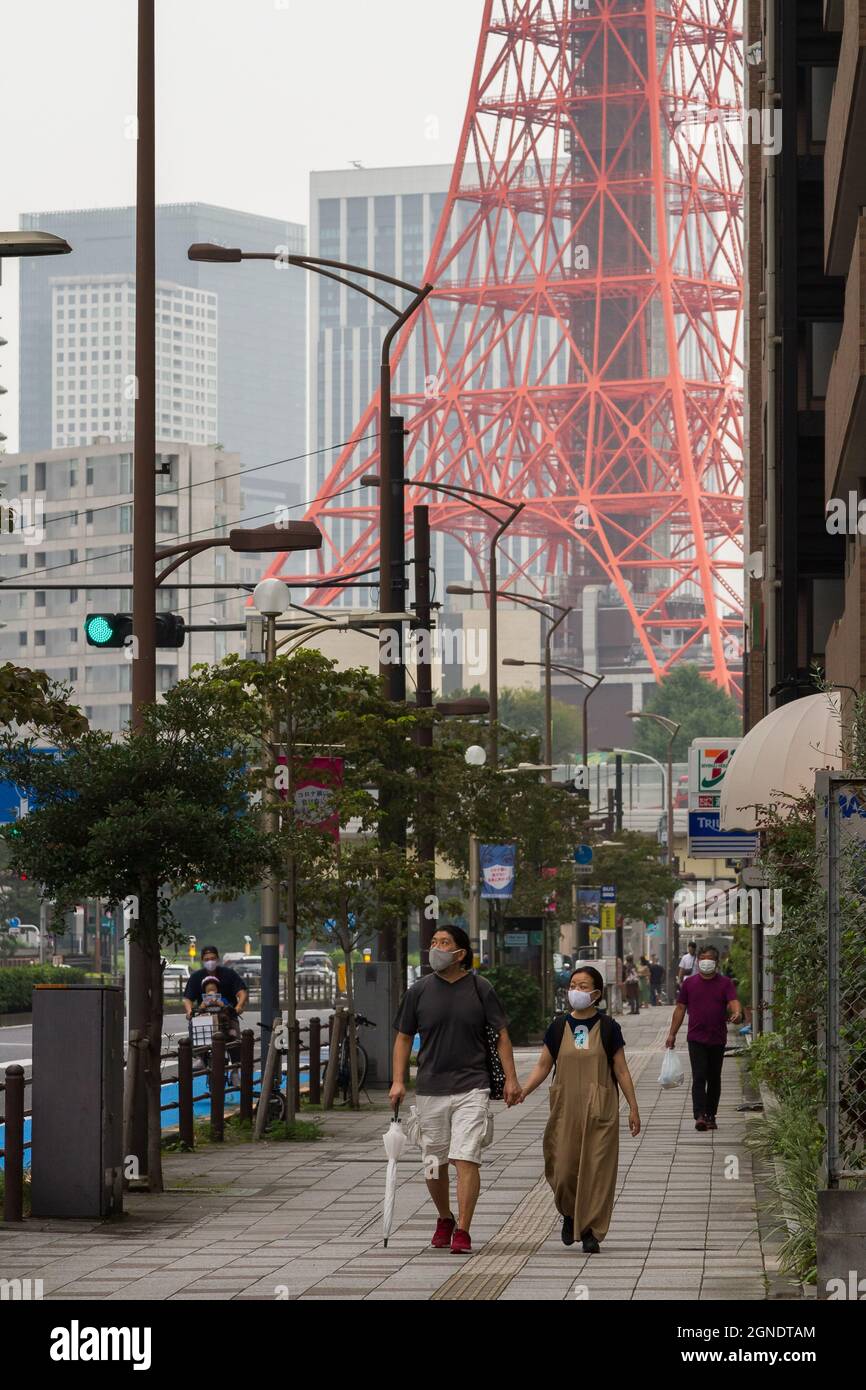 People wearing face masks against COVID-19 walk along a street in Tokyo ...