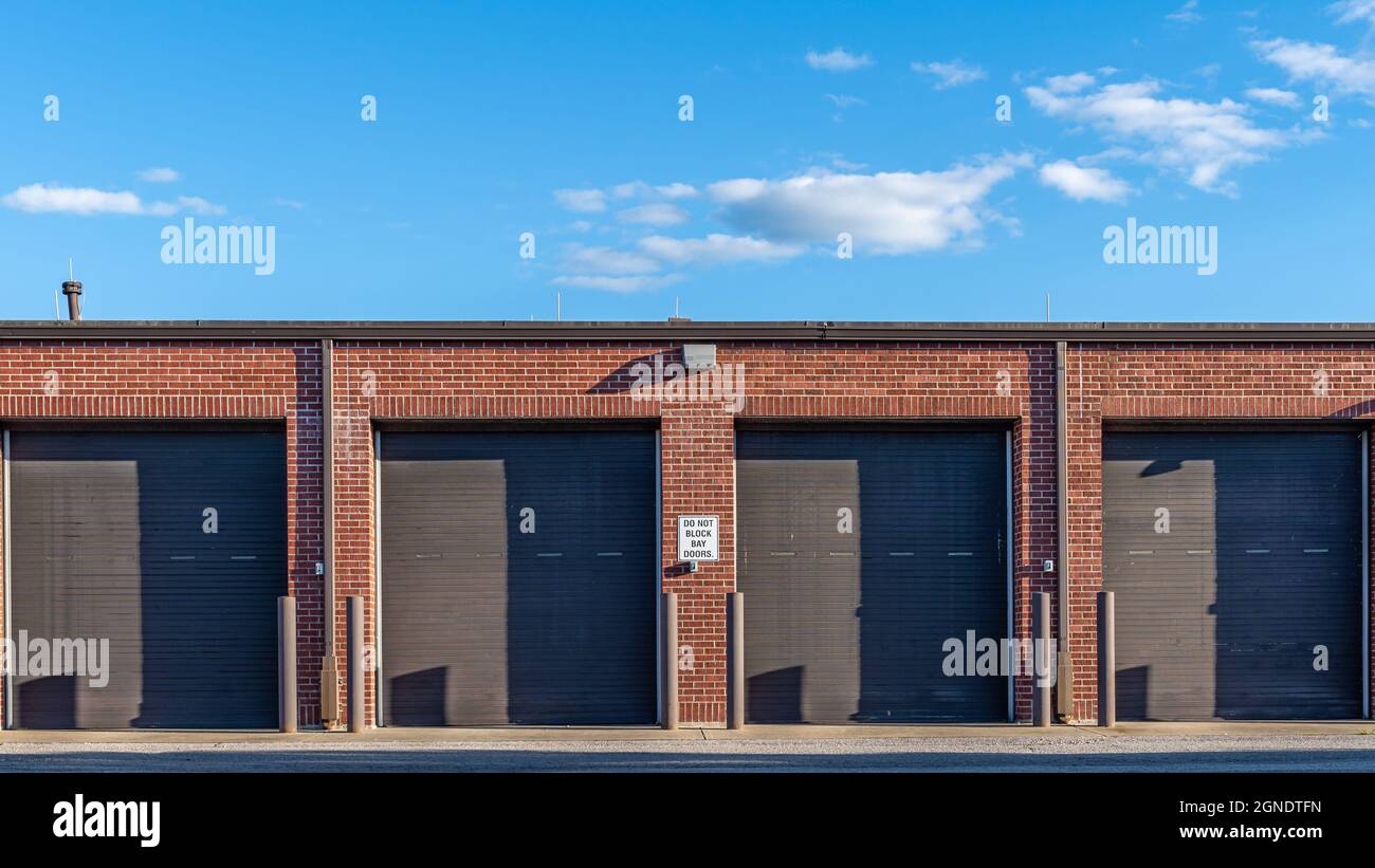 Maintenance bay garage doors on a brick building. The sky above is an a ...