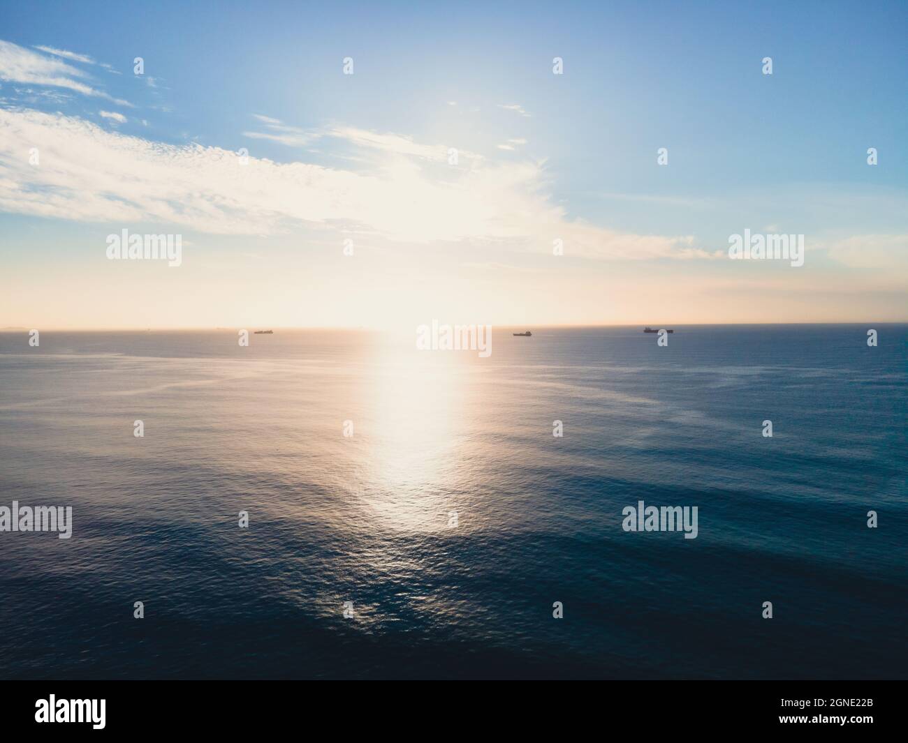 Drone view of sunrise over ocean with maritime boats seen in distance ...