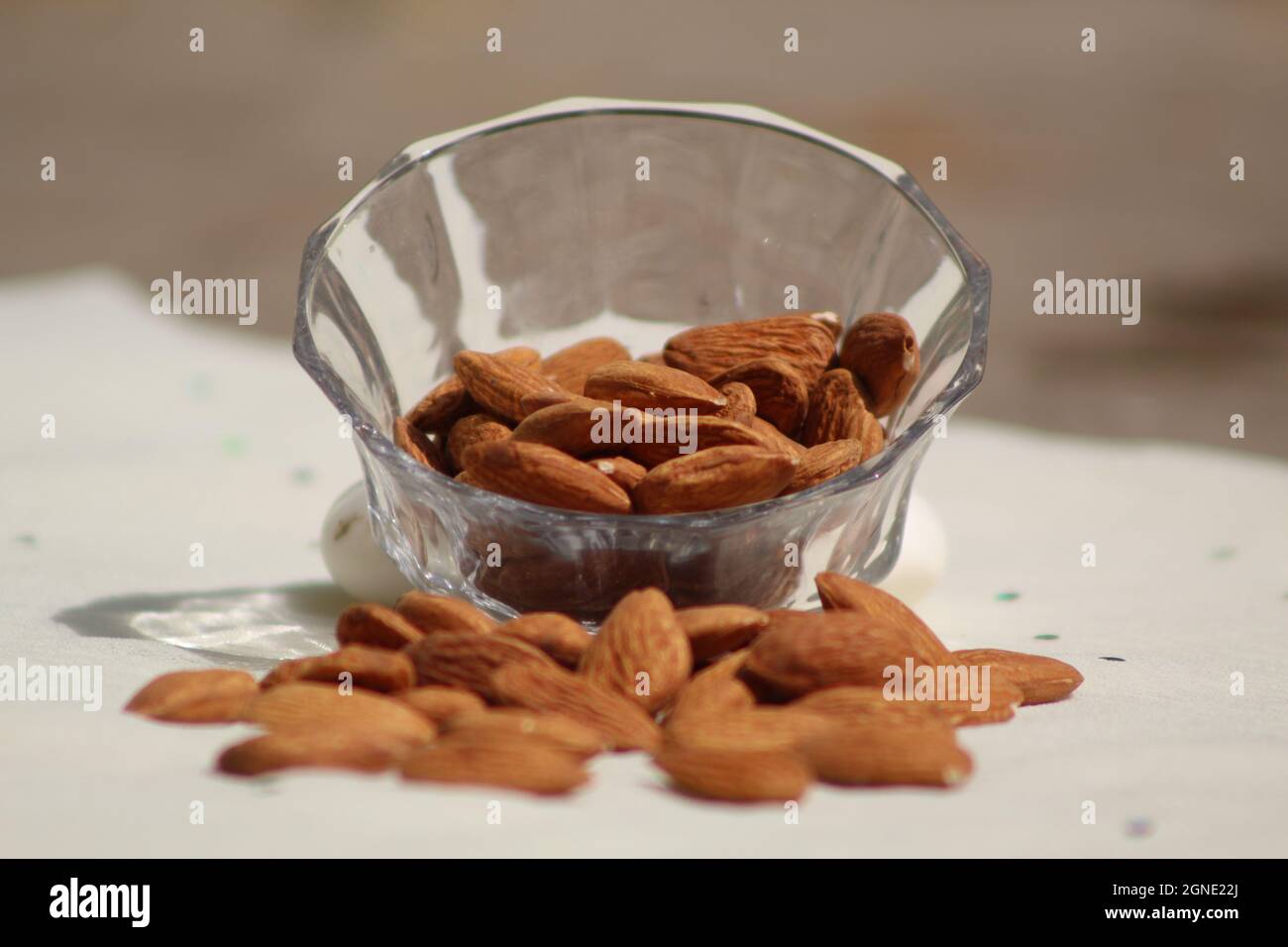 Almonds falling down from the glass bowl on white background Stock ...