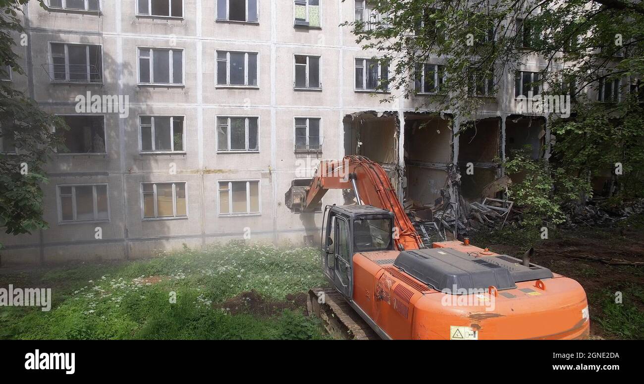 An excavator destroys the building with its bucket Stock Photo - Alamy