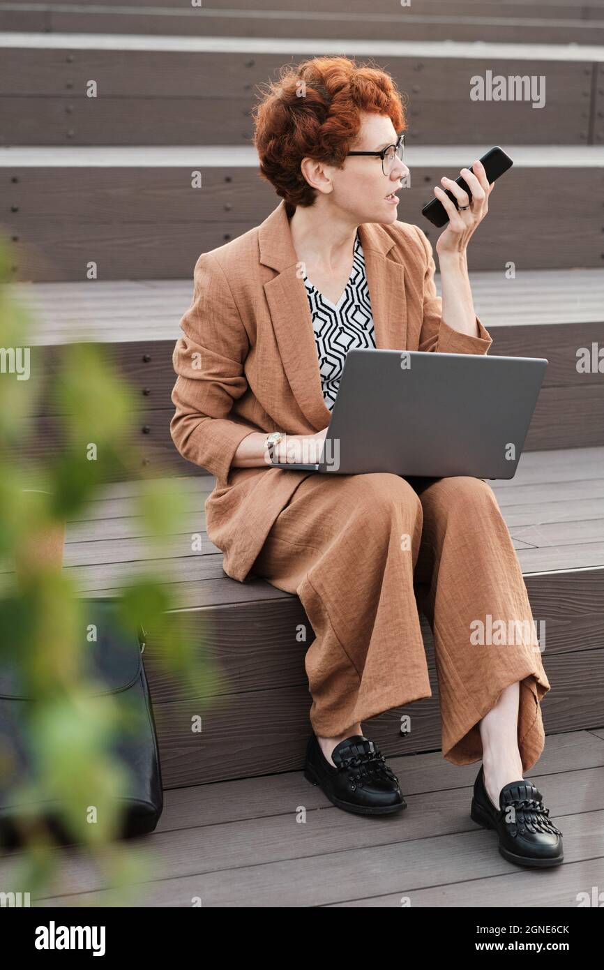 Vertical portrait shot of mature Caucasian woman with red hair wearing ...