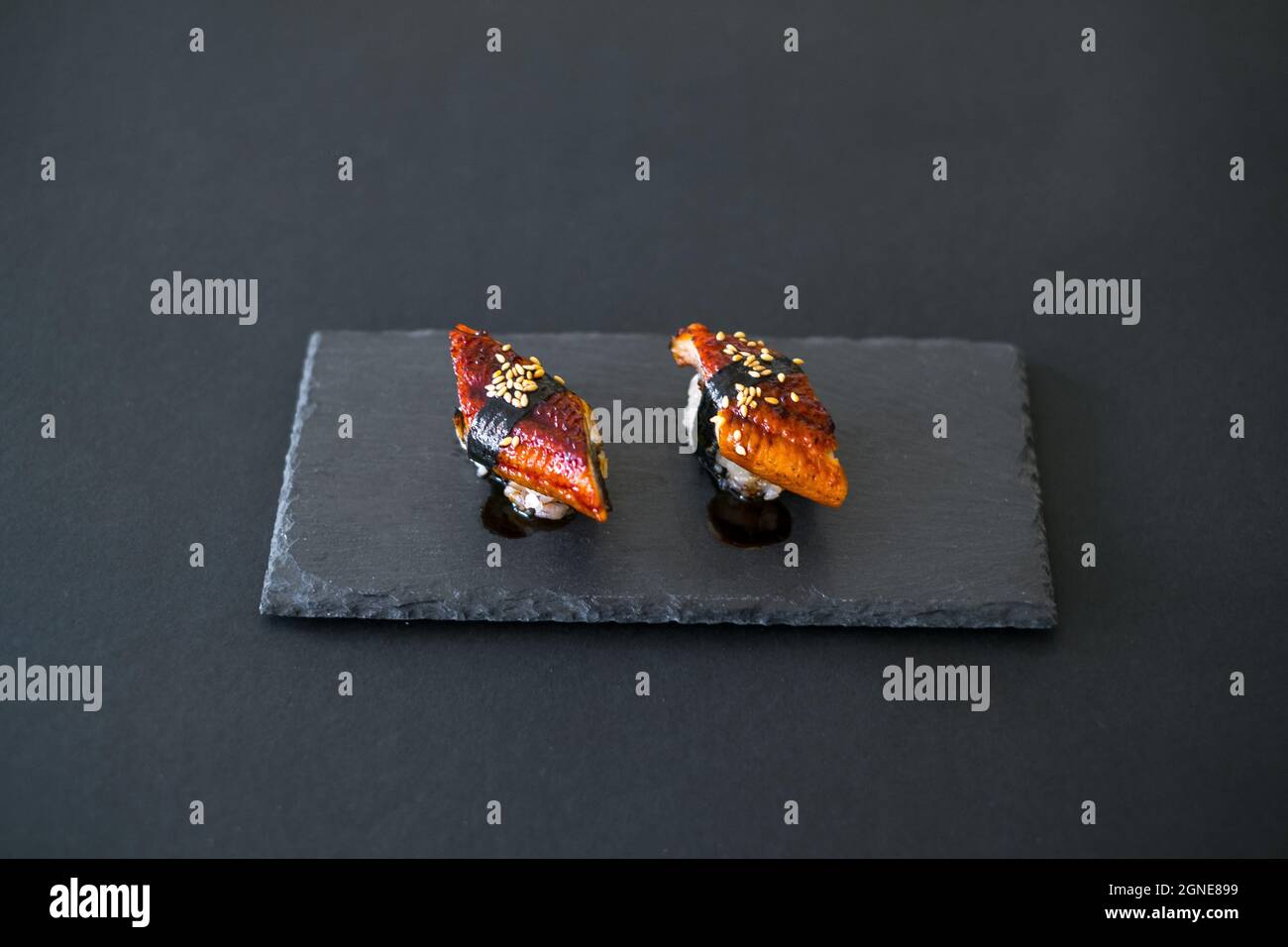 Japanese Sushi - Two Unagi Nigiri Sushi on black stone board. Sushi pieces served on black slate ...