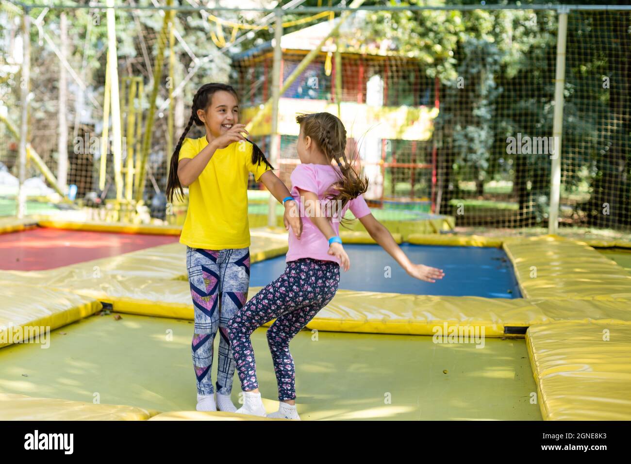 Little pretty girls having fun outdoor. Jumping on trampoline in ...