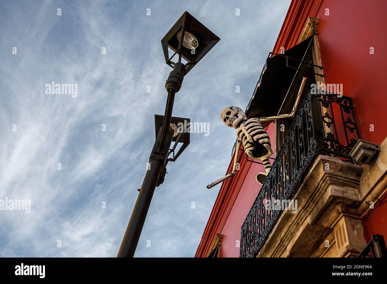 Low-angle shot of a creepy skeleton on the balcony of a red building on ...