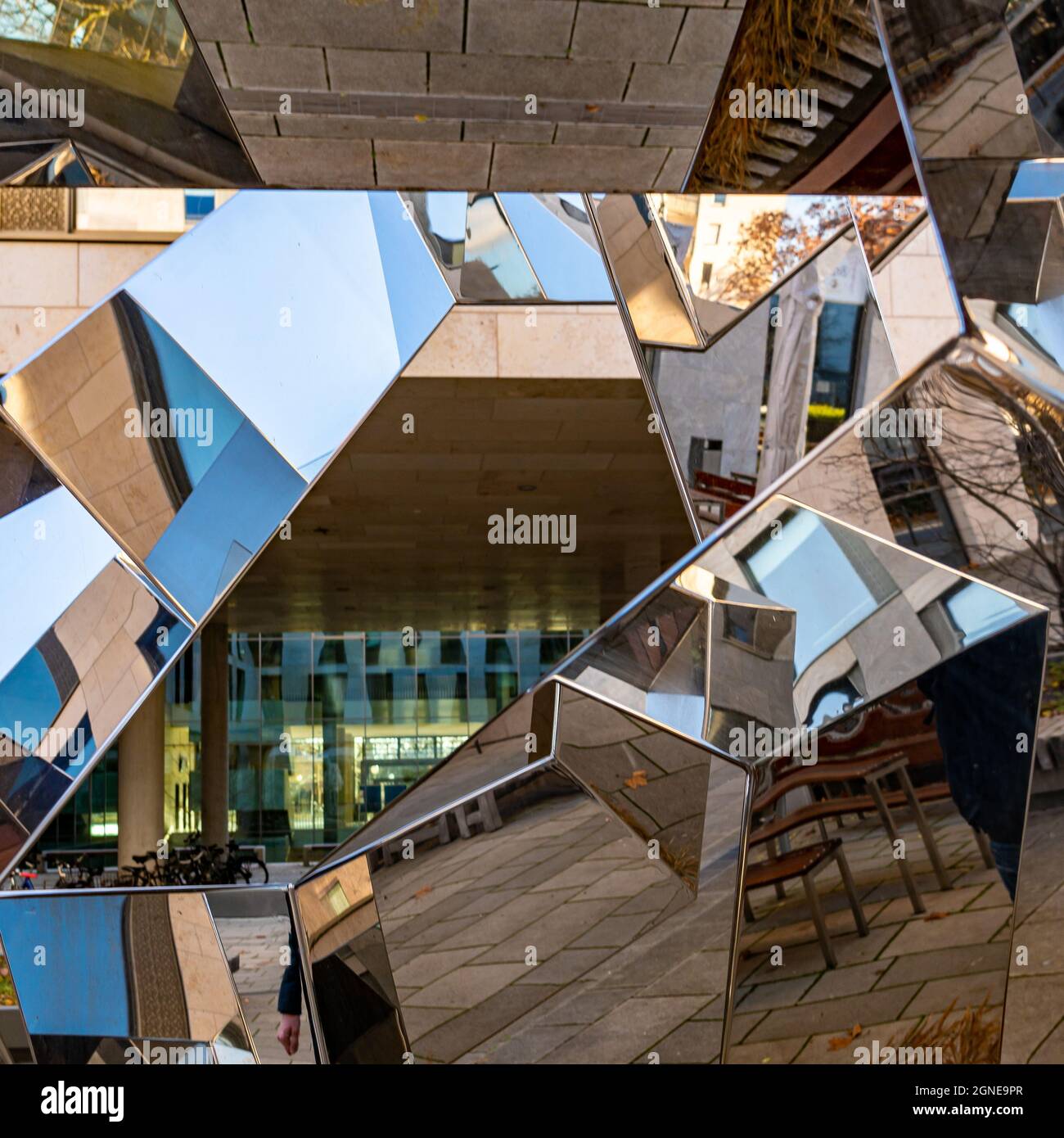 Abstract mirror structure in front of a building reflecting the ...