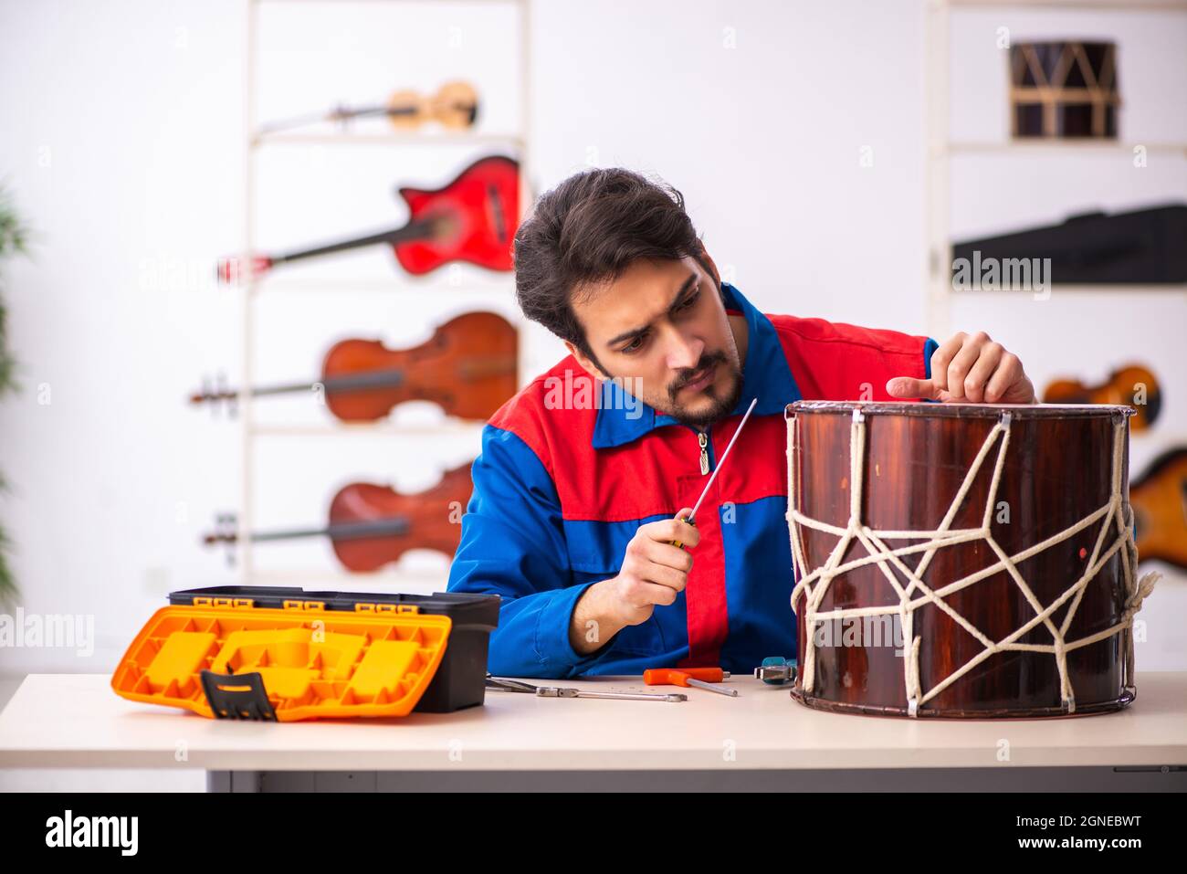 Young repairman repairing musical instruments at workplace Stock Photo ...