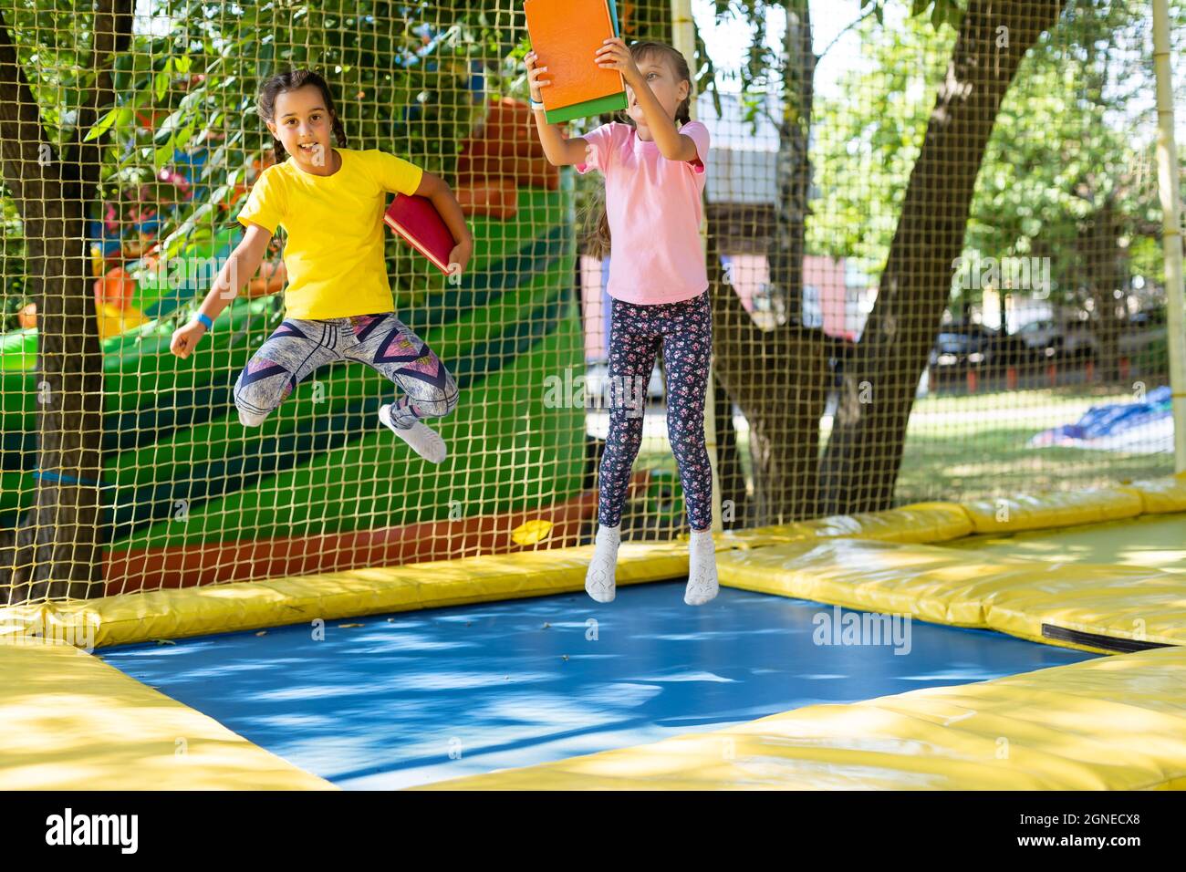 Little pretty girls having fun outdoor. Jumping on trampoline in ...