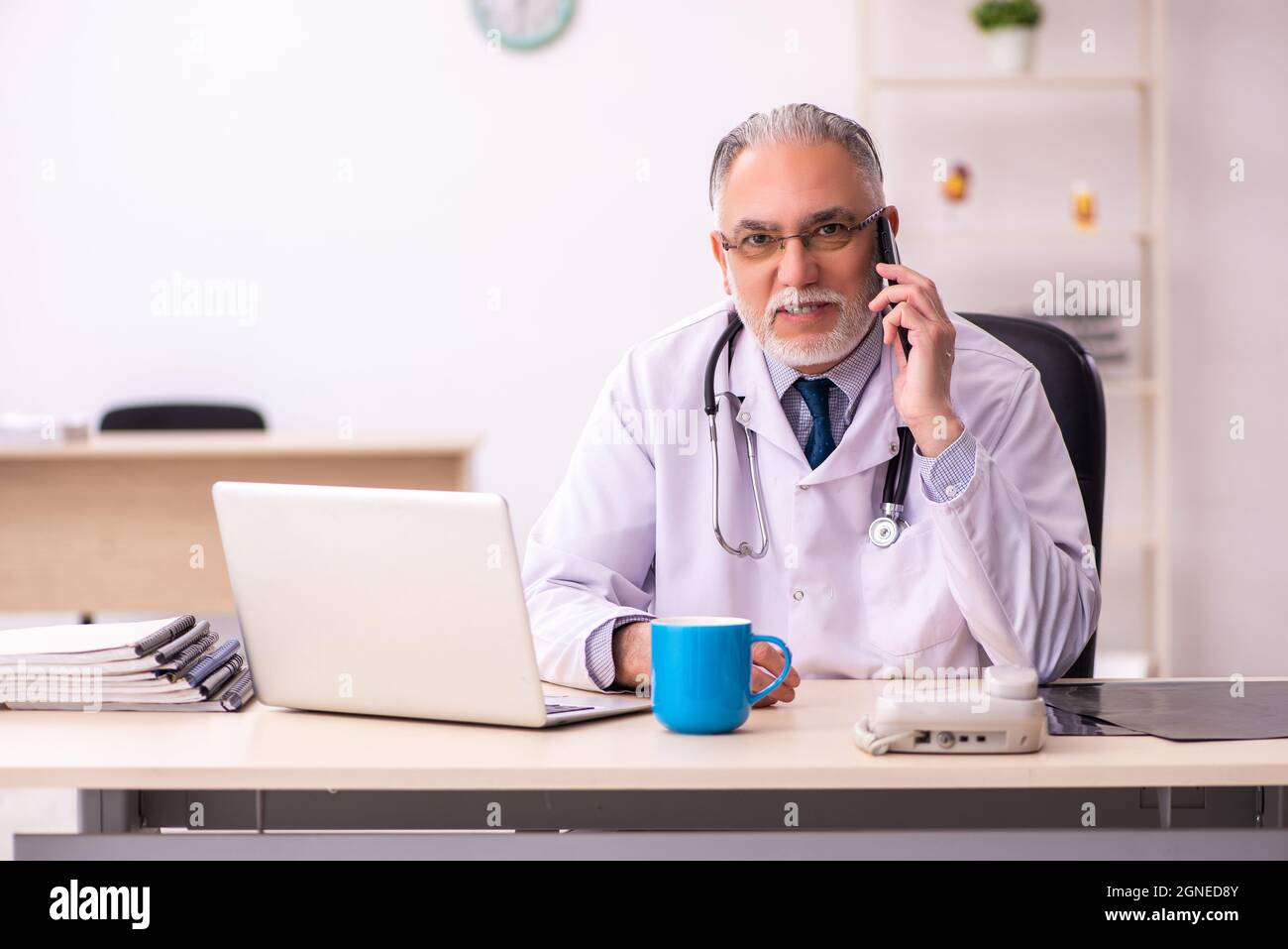 Aged male doctor working at workplace Stock Photo - Alamy