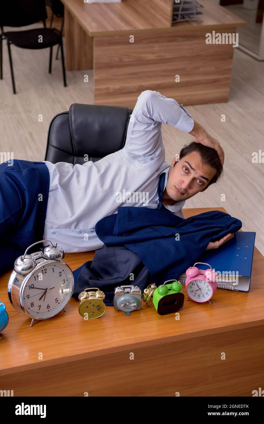 Young businessman sleeping in the office in time management concept ...