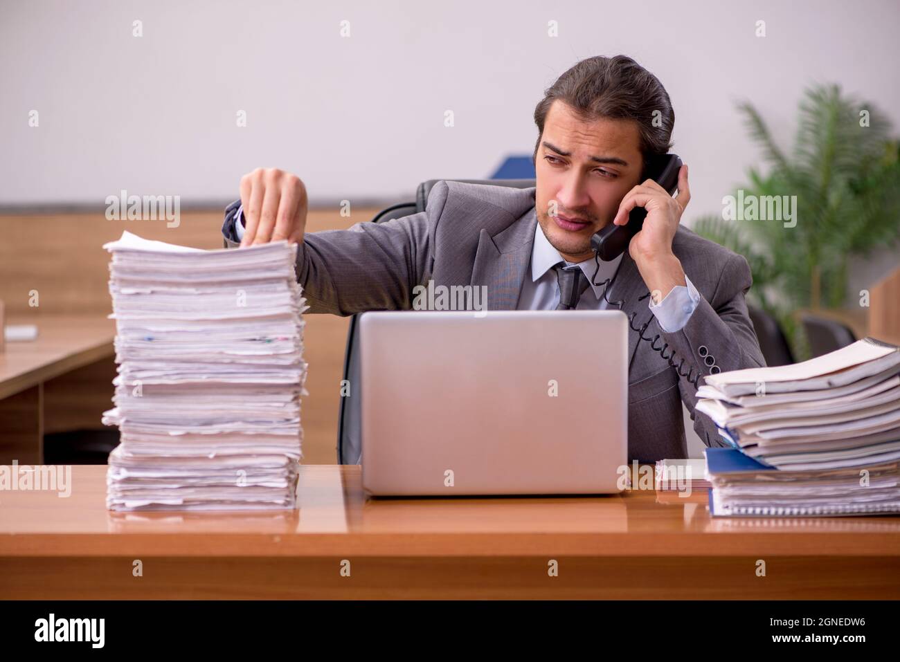 Young employee and too much work in the office Stock Photo - Alamy