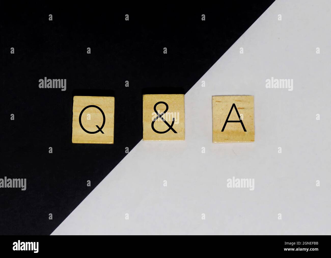 Wooden alphabet tiles with Q and A letter on black and white paper ...