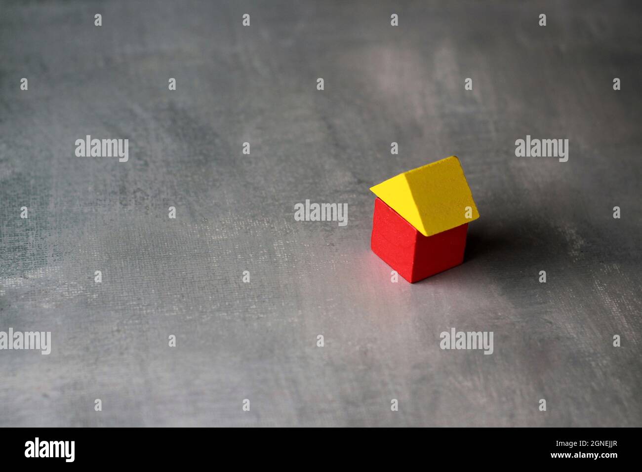House made from wooden cubes on concrete floor. Copy space for text ...