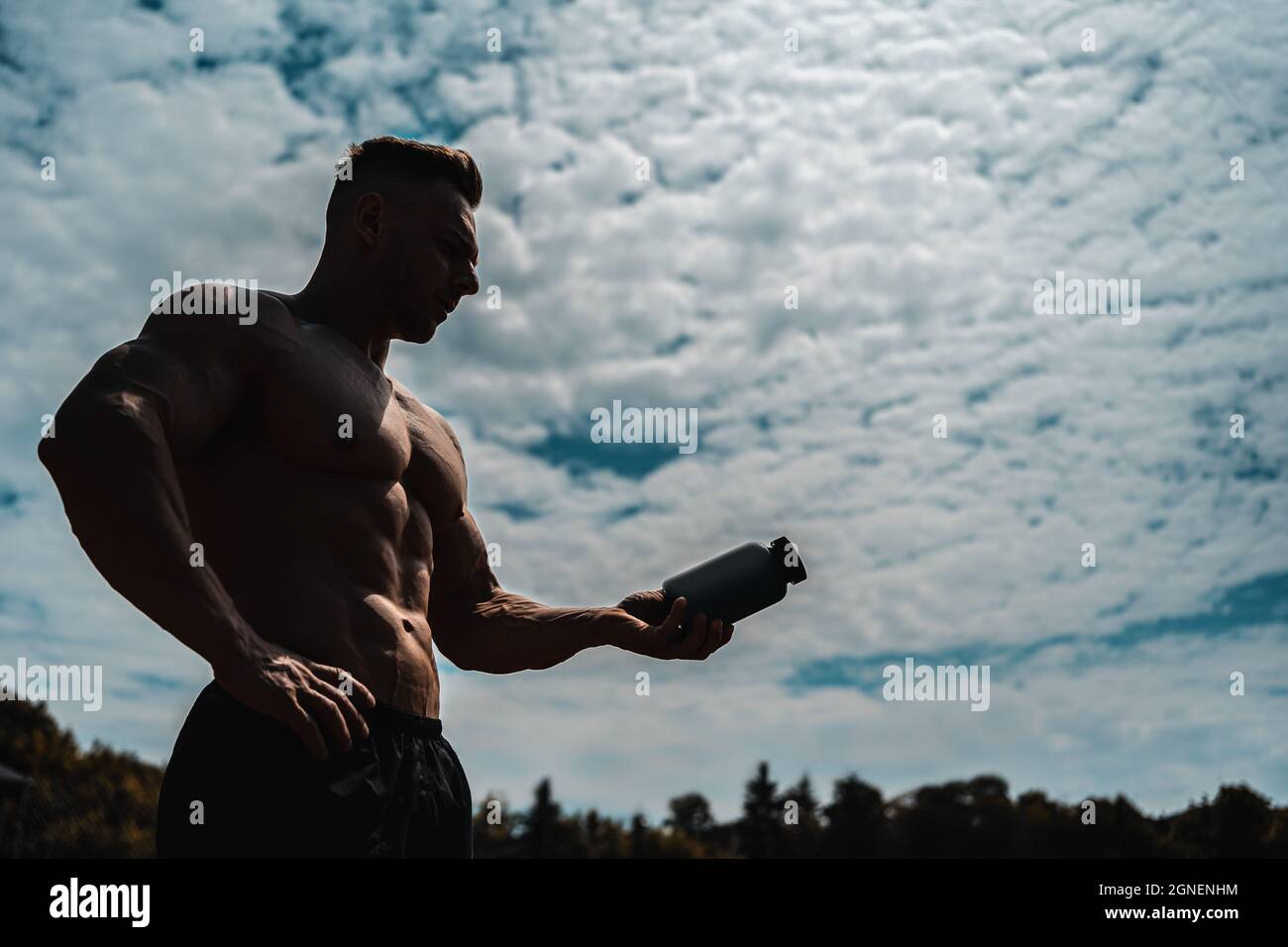 muscular athlete man holding container with protein powder or vitamin ...