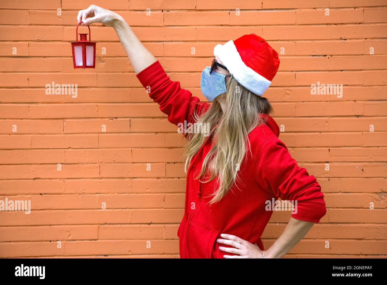 Profile of blond girl in silver mask, red hat and black sun glasses ...