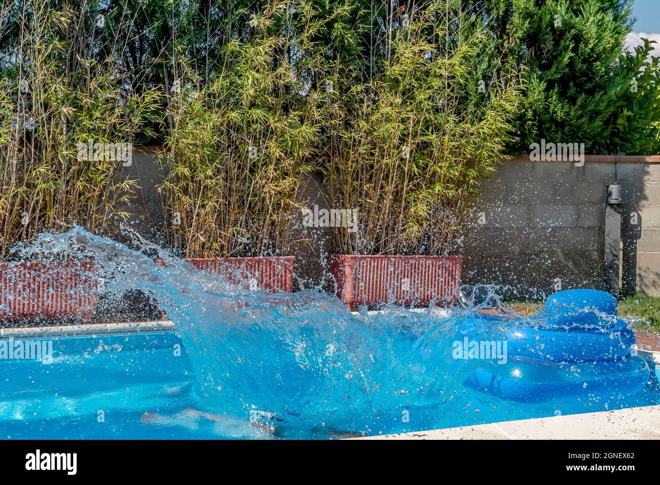 A huge splash of water is created by a cannonball dive into a swimming ...