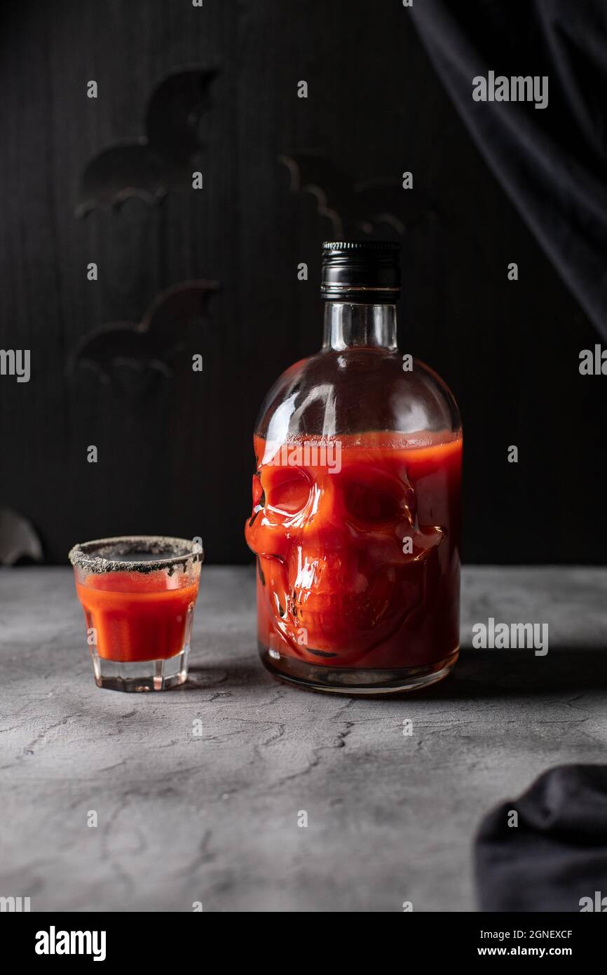 Tomato cocktail in a skull-shaped bottle and glasses. Drink for ...
