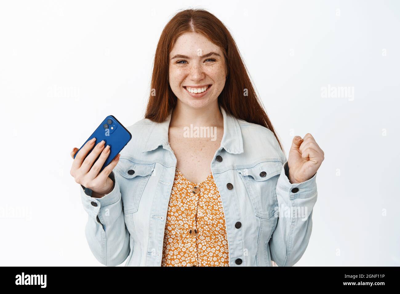 Happy girl holding mobile phone and celebrating, looking satisfied ...