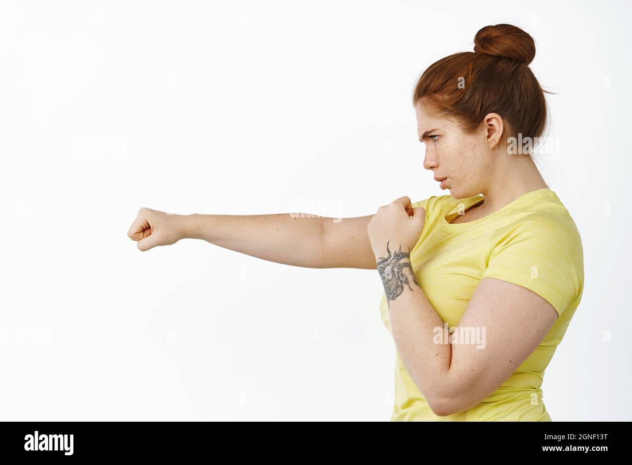 Profile portrait of serious redhead woman shadow boxing, doing box ...