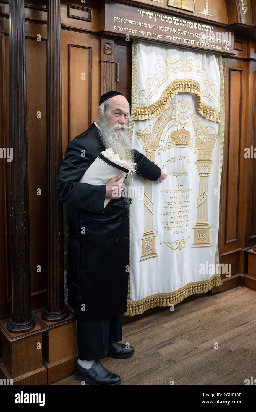 A rabbi in a synagogue points to a spot on the Torah Ark that mentions ...