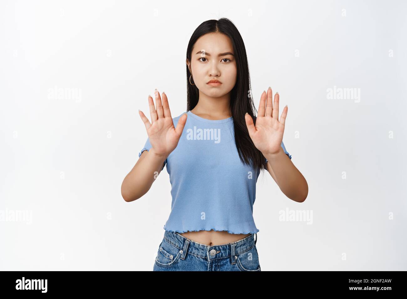 Serious asian girl shows block stop gesture, refusing, frowning and ...