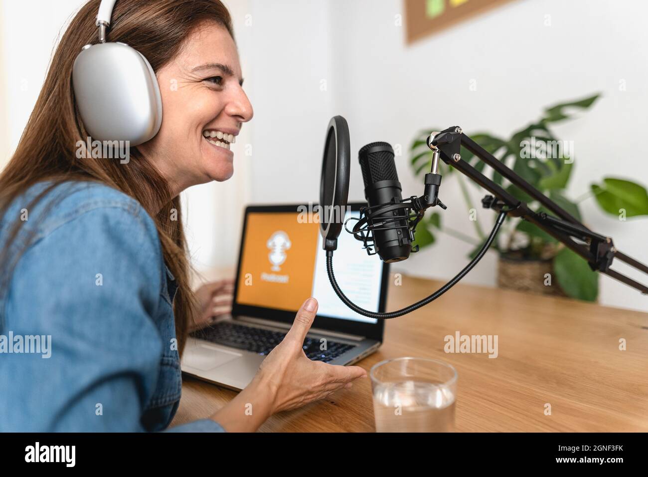 Mature woman recording a podcast using microphone and laptop from her ...