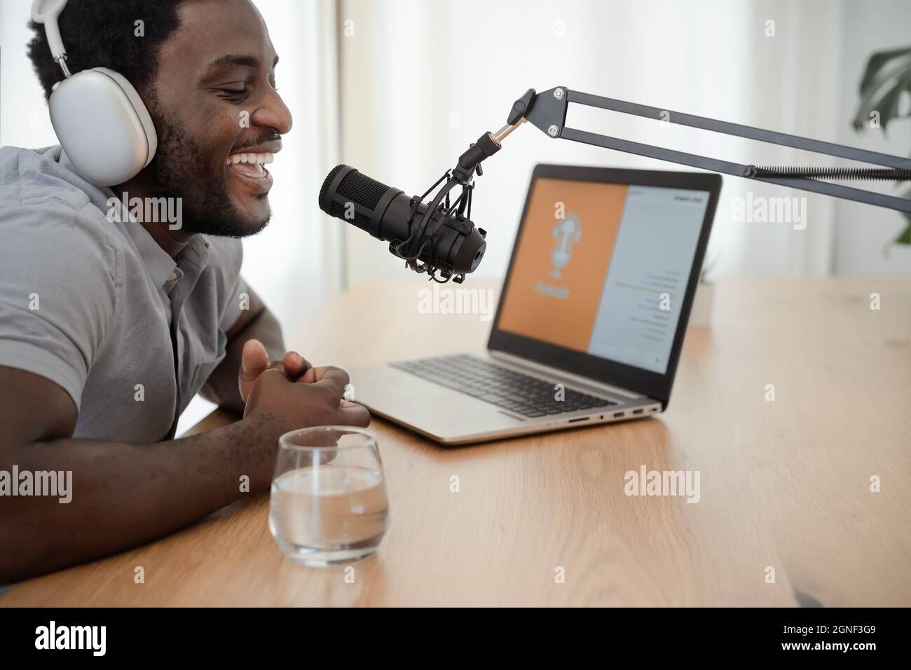 African man recording a podcast using microphone and laptop from his ...