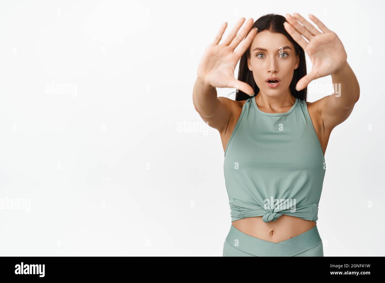 Image of sportswoman looking through hand frames with surprised ...